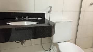 Casa de banho com lavatório de bancada preta, sanita branca e chuveiro.