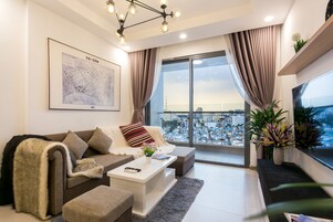 Uma sala de estar moderna com sofá, mesa de centro e uma grande janela com vista para a cidade.