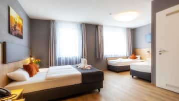 Quarto de hotel com uma cama grande, uma cama menor, uma mesa com telefone e um quadro na parede.