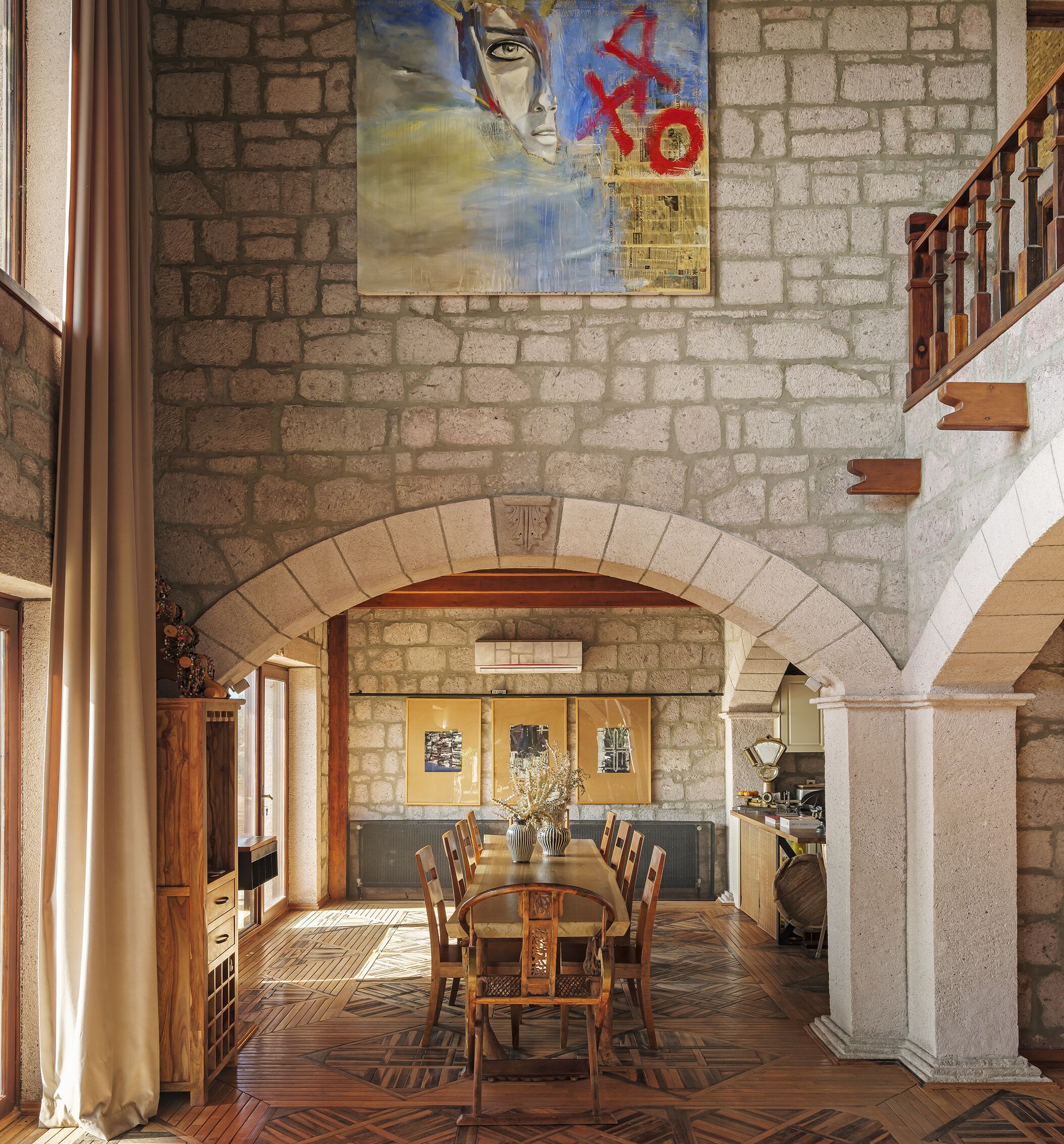 Uma sala de jantar ampla com teto de pedra alto, mesa de madeira e cadeiras.