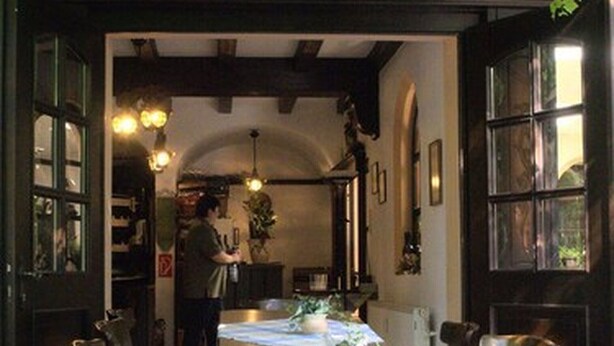 Uma sala de jantar com uma longa mesa de madeira, cadeiras estofadas em azul e um candelabro.