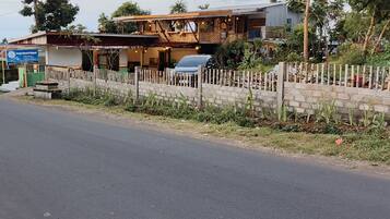 Um edifício com uma placa, um carro estacionado em frente e uma motocicleta com o condutor.