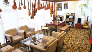 Uma sala de estar com sofá, mesa de centro, estante de livros e um violão.