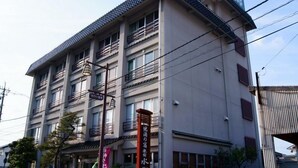 Um edifício de vários andares com varandas, sinalização e um telhado tradicional com azulejos.