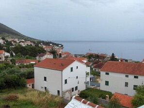 Uma vila costeira com edifícios brancos e telhados vermelhos, com vista para o mar.