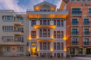 Hotel de vários andares com entrada central, varandas e uma placa indicando um restaurante.