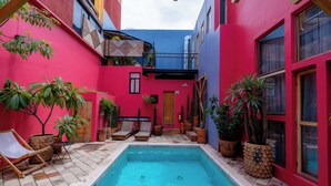 Um pátio com piscina, plantas em vasos e área de estar externa.