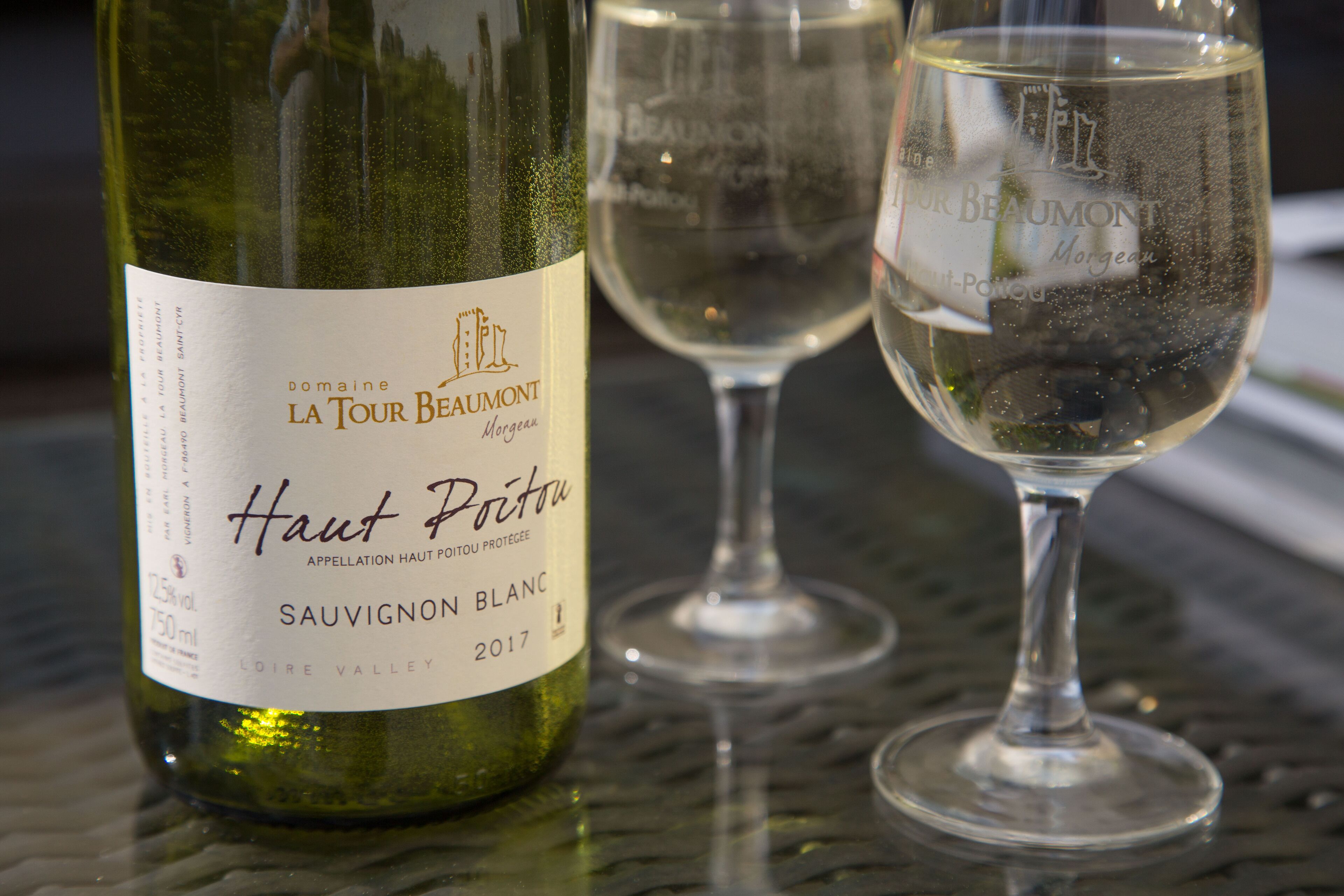 Uma garrafa de vinho Haut Poitou e dois copos sobre uma mesa.