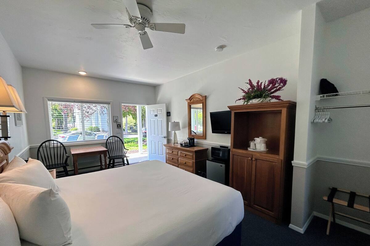 Quarto de hotel com uma cama, uma mesa com cadeira, televisão, cafeteira e vista para o exterior.
