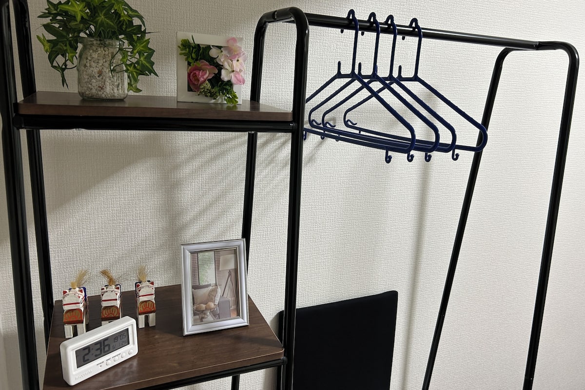 Uma estante de metal com um relógio, uma pequena planta e um quadro emoldurado.