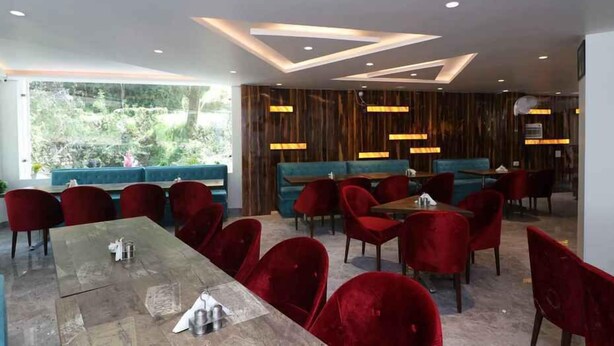 Um restaurante com cadeiras vermelhas, um sofá azul e uma parede de madeira.