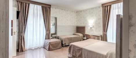 Quarto de hotel com duas camas, uma área de estar e um banheiro.