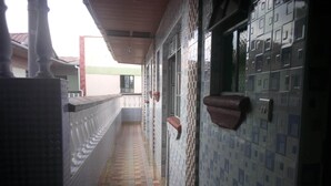 Um corredor com paredes e chão revestidos de azulejos estampados, que dá para um quarto com janela e porta.