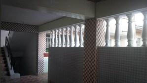 Um corredor com paredes estampadas, uma escadaria e um balcão com grades brancas.