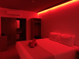 Quarto de hotel com uma cama, um guarda-roupa e uma escrivaninha.