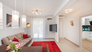 Uma sala de estar moderna com um sofá, tapete vermelho e uma mesa de jantar com um vaso de flores.