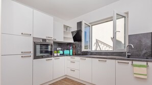 Uma cozinha moderna com armários brancos, forno embutido, micro-ondas, pia e janela com vista.