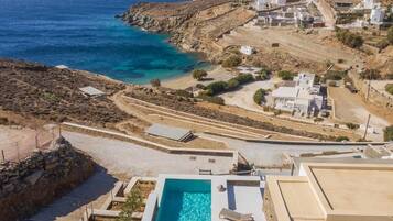 Uma propriedade costeira com piscina, casas em terraços e vista para o mar.