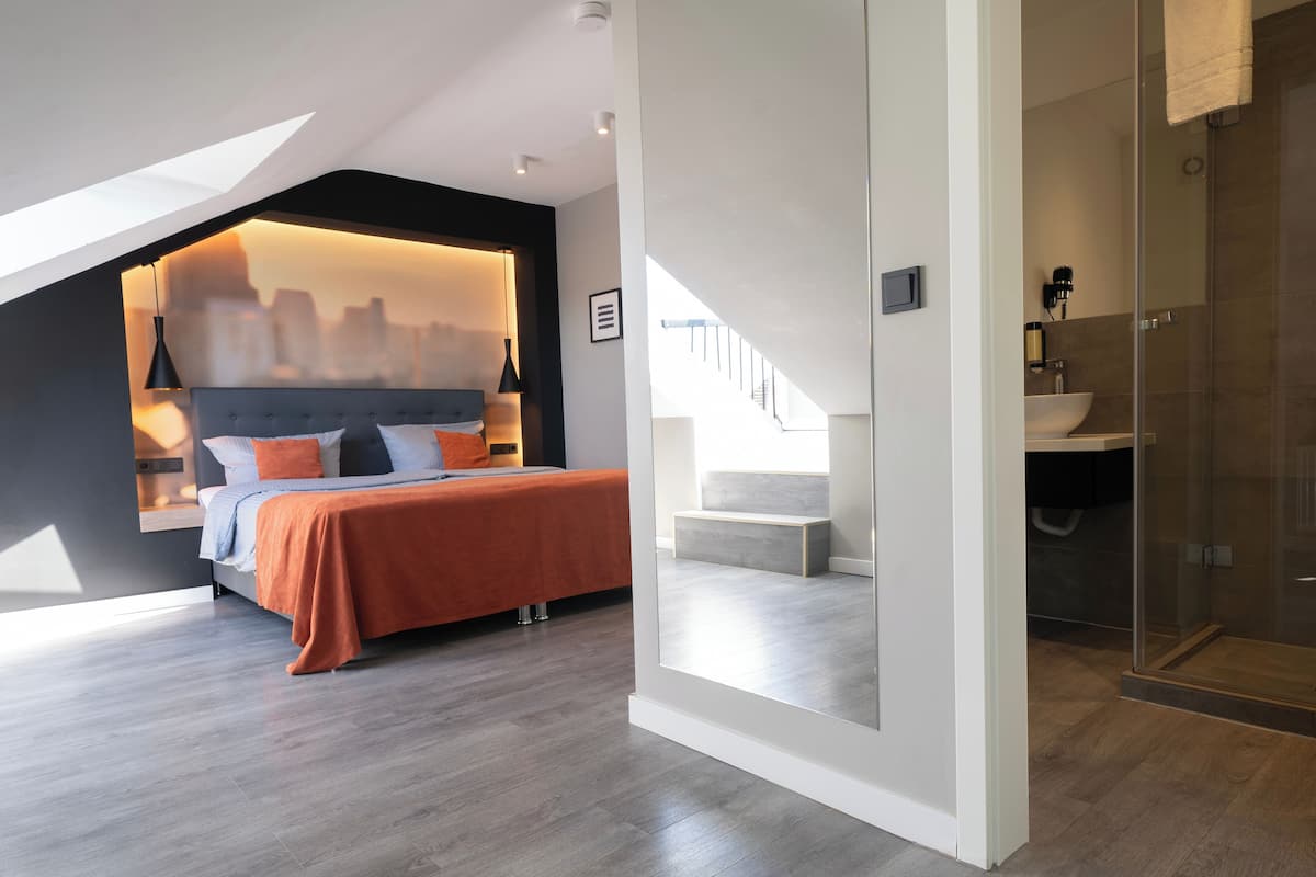 Quarto moderno com cama, mesa de cabeceira e uma janela grande.