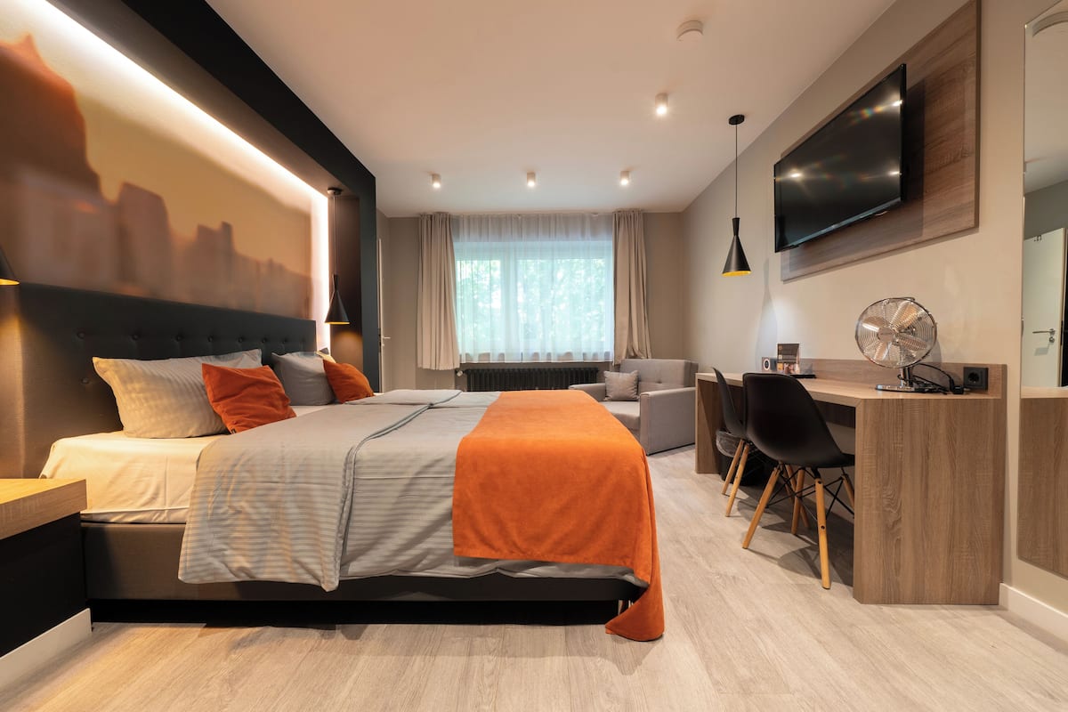 Quarto de hotel moderno com cama, escrivaninha e área de estar.