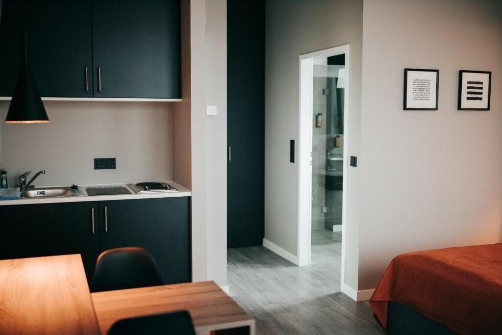 Quarto de hotel compacto com cozinha americana, área de refeições e cama.