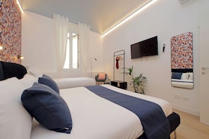 Quarto de hotel moderno com uma cama grande, uma escrivaninha, uma cadeira, uma televisão e um espelho.