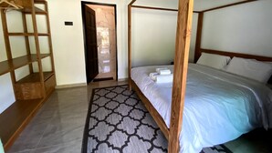 Quarto com cama de dossel, guarda-roupa de madeira e tapete estampado.