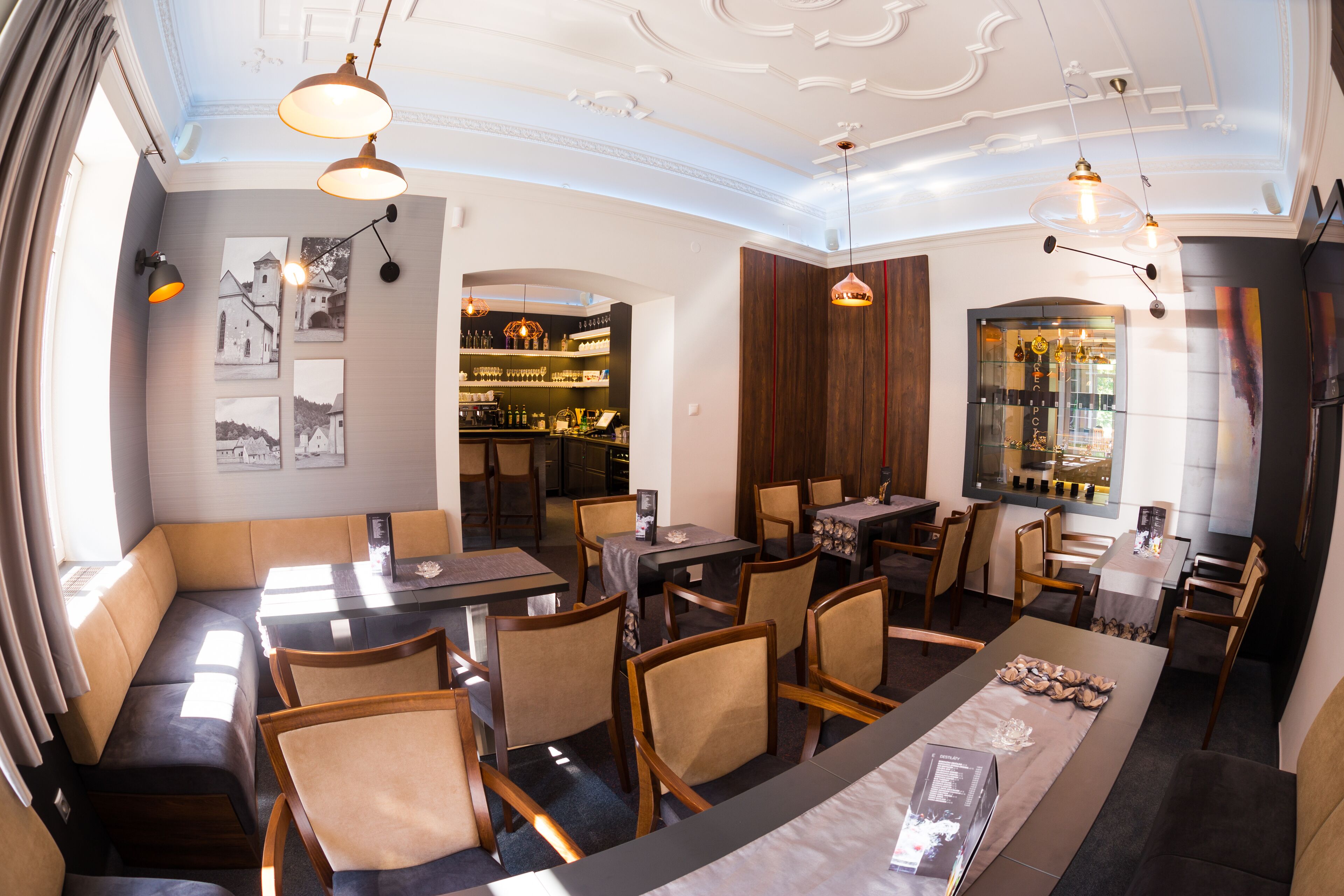 Um restaurante com área de bar, diversas opções de assento incluindo cabines e mesas, e vários lustres pendentes.