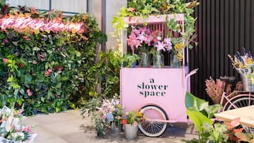Um carrinho rosa com a inscrição 'um espaço mais lento', com plantas e flores em vasos.