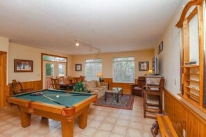 Uma sala de estar aconchegante com mesa de bilhar, assentos confortáveis e uma televisão.