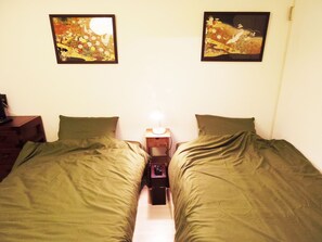 Quarto com duas camas, uma mesa de cabeceira com abajur e duas quadros pendurados na parede.