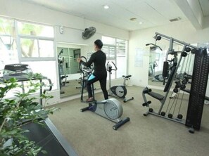 Uma academia com equipamentos de ginástica, incluindo um aparelho elíptico e máquinas de musculação.