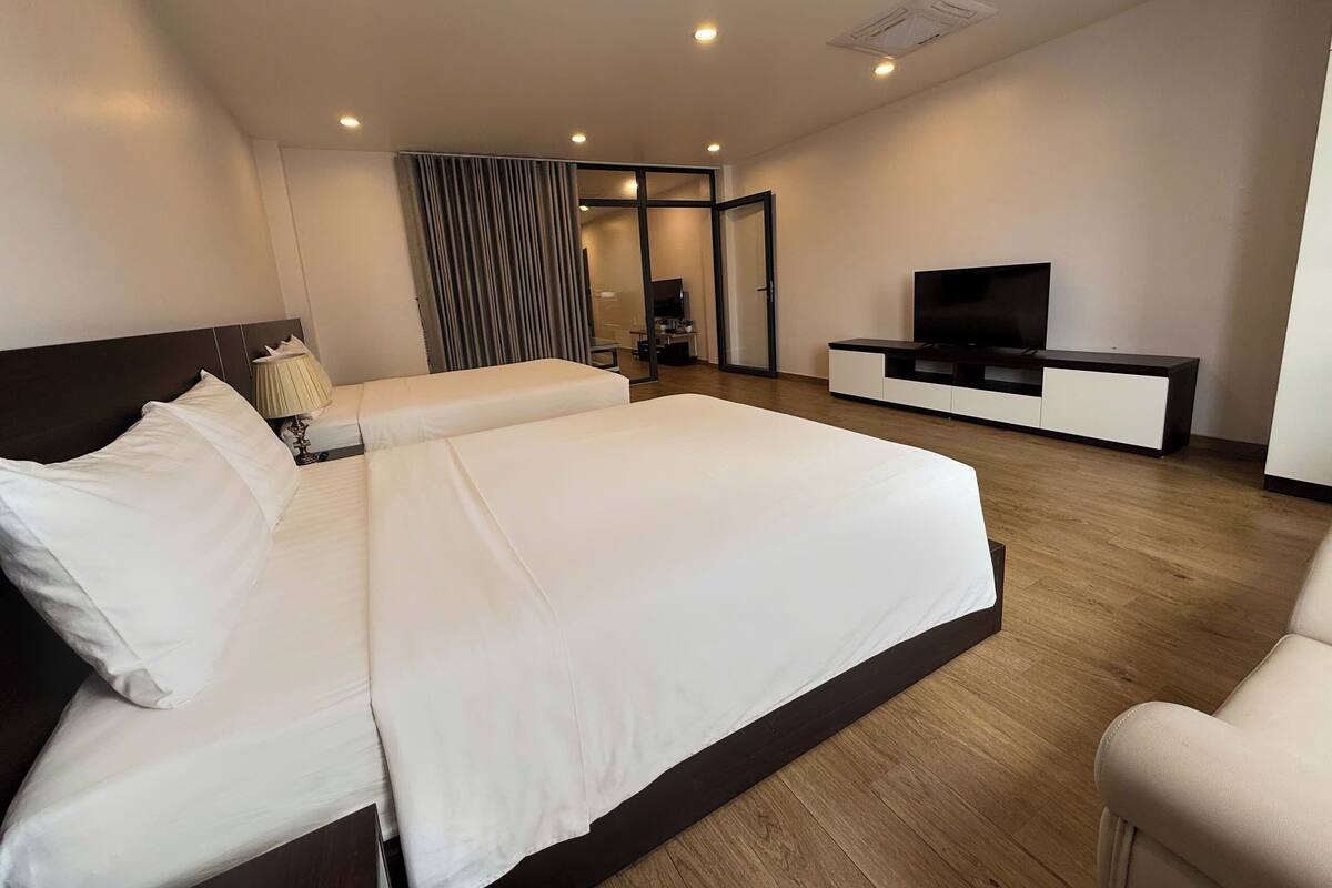 Quarto de hotel moderno com uma cama grande, uma televisão e uma escrivaninha.