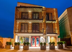 Um hotel com fachada moderna, várias varandas e uma porta de entrada vermelha.