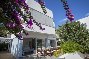 Uma casa moderna de dois andares com um pátio com mobiliário de exterior.