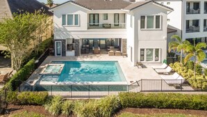 Uma casa moderna de dois andares, com piscina, área de estar externa e um jardim bem cuidado.