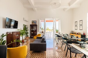 Uma sala de estar espaçosa com sofá, poltrona amarela e mesa de jantar com cadeiras.