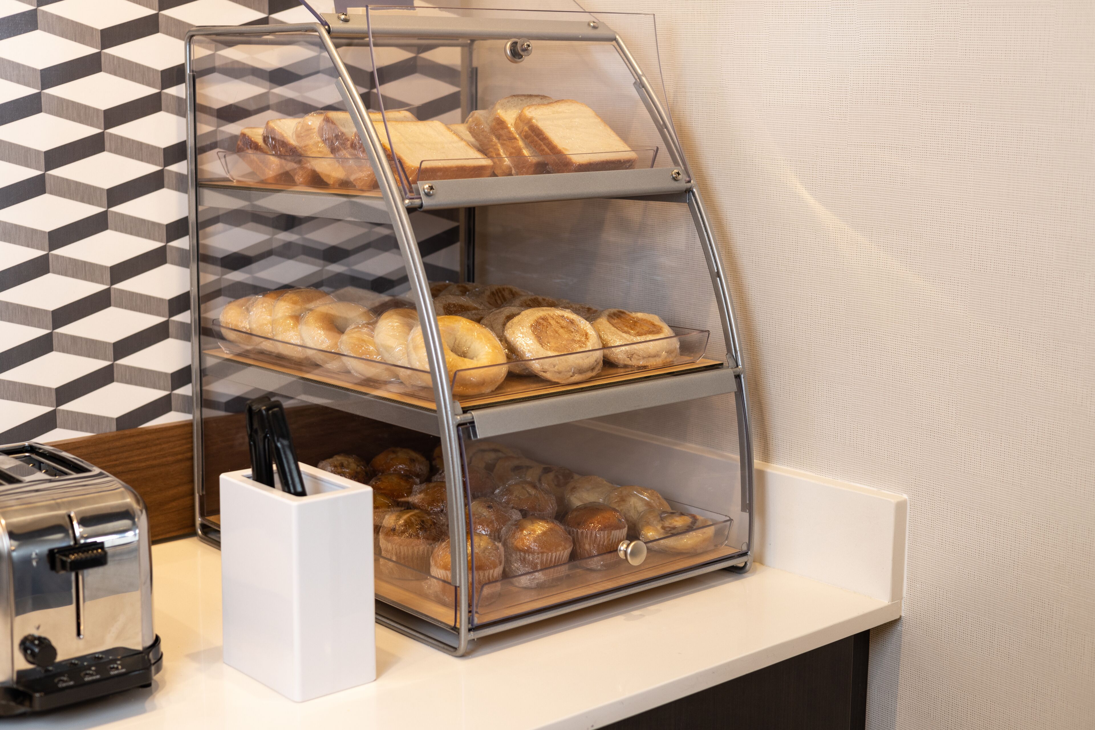 Vitrine de café da manhã com diversos pães e doces.