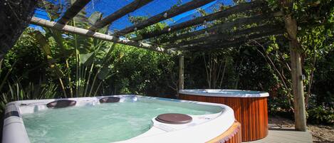 Uma área de hidromassagem com deck de madeira e uma estrutura de pérgola.