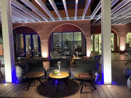 Uma área de estar moderna com piso de madeira, assentos acolchoados e iluminação suave.