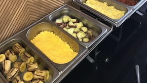 Buffet com diversos alimentos, incluindo bananas, ovos e carne.