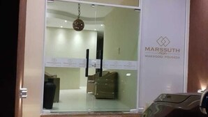 Um edifício moderno com entrada de vidro, um lustre pendurado e um carro estacionado na frente.