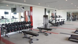 Uma academia com esteiras, halteres, bancos e aparelhos de musculação.
