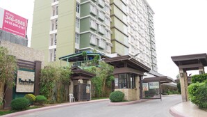 Edifício residencial de vários andares com fachada verde, entrada com portão e placa indicando limite de velocidade de 15.