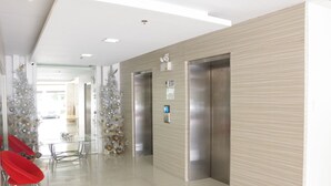 Um lobby moderno com uma mesa de vidro, cadeiras vermelhas e um pinheiro de Natal.