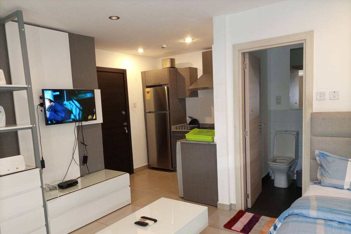 Quarto de hotel compacto com cozinha compacta, televisão, cama e banheiro.