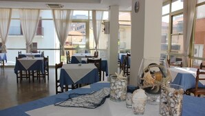 Uma área de refeições com mesas preparadas para dois, com decoração temática náutica com conchas e estrelas-do-mar.