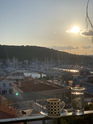 Uma marina com barcos, céu claro e um pôr do sol.