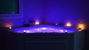 Uma banheira de hidromassagem com velas e copos de vinho.