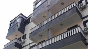 Um edifício residencial de vários andares, com varandas, aparelhos de ar condicionado e fachada plana.